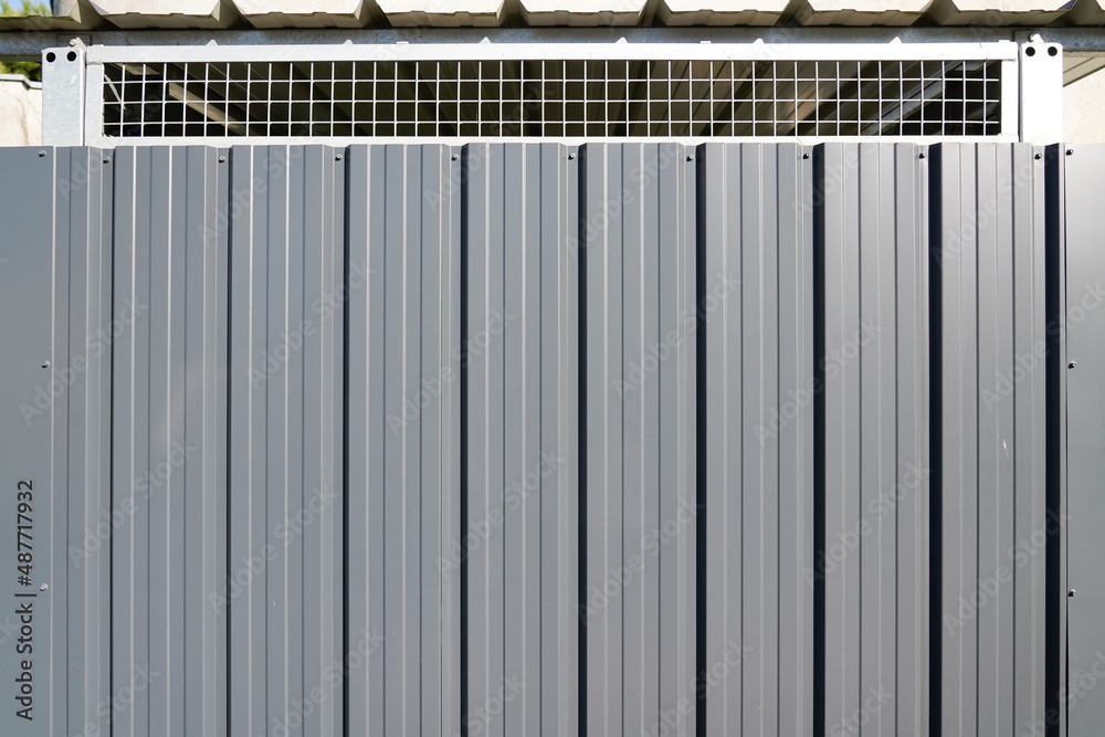steel vertical striated metal wall with mesh on the upper part ...