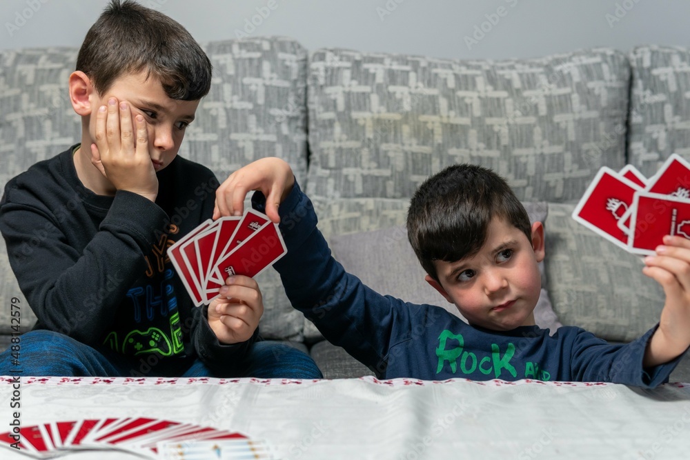 A couple of kids playing cards at grandma's house. Two young rivals ...
