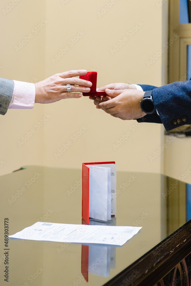 Notary handing the rings to the husband on top of the marriage contract ...