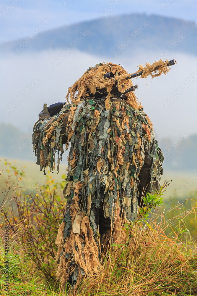 detail of camouflage Ghillies sniper with rifle on his shoulder ...