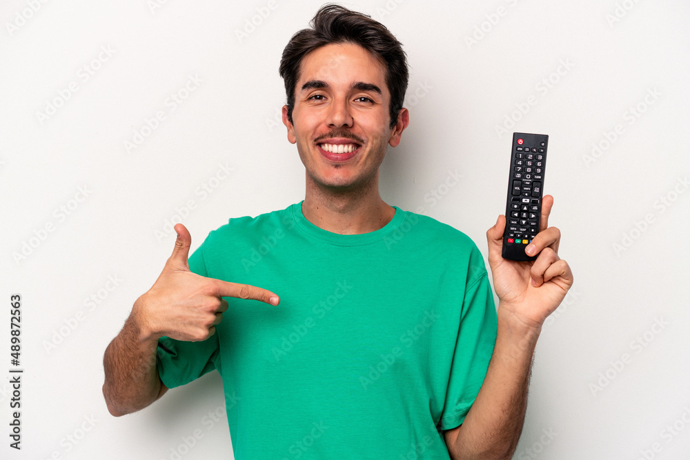 Young caucasian man holding a tv remote isolated on white background ...