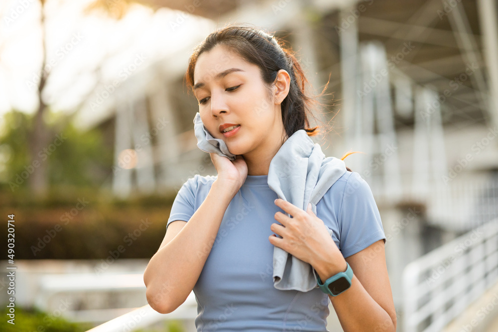 Asian woman wiping sweat on face and neck during exercise in the city ...