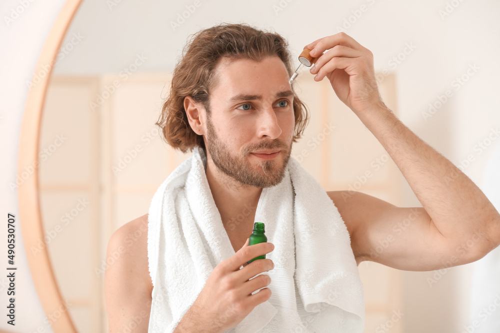 Young man using serum for skin care in bathroom Stock Photo | Adobe Stock