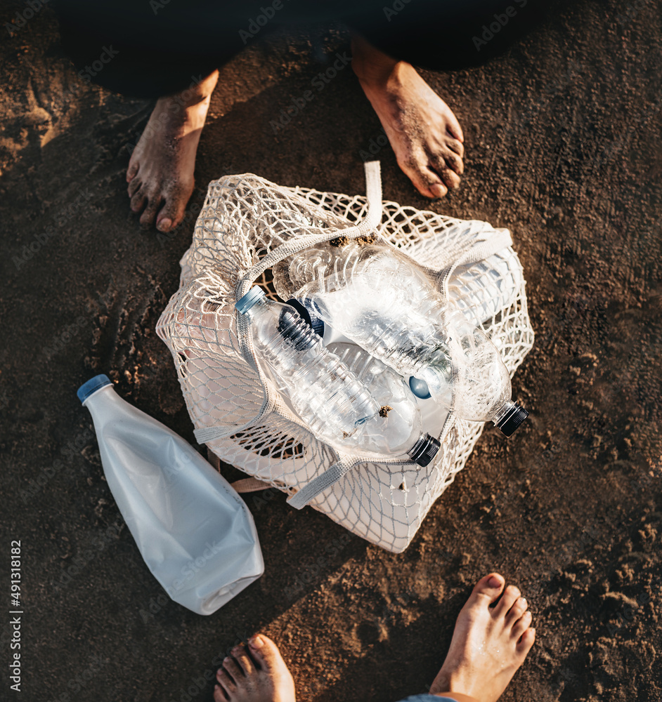 top view of an ecological bag on the beach sand filled with plastic ...