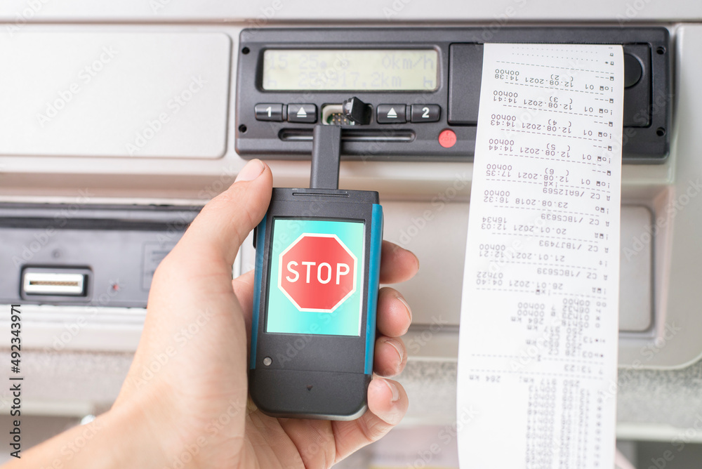 Driver holding a digital tachograph reader with big red stop mark on ...