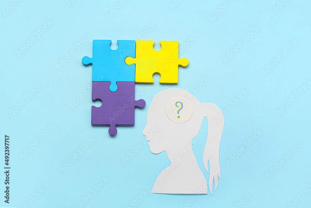 Paper female head with question mark and puzzle pieces on blue ...