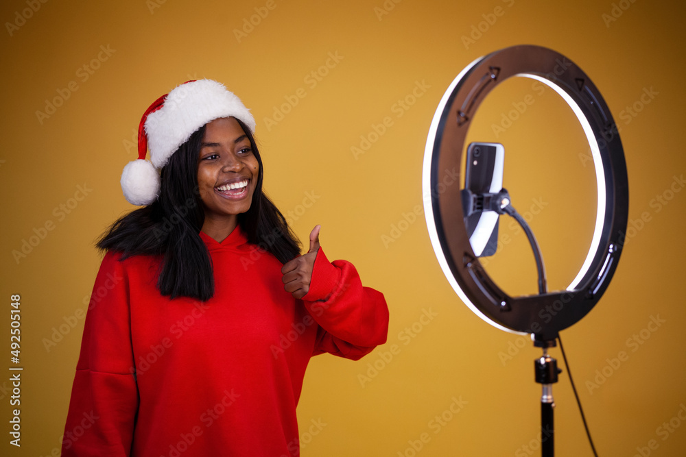 smiling african-american girl vlogger in a red hoodie and a Santa hat ...