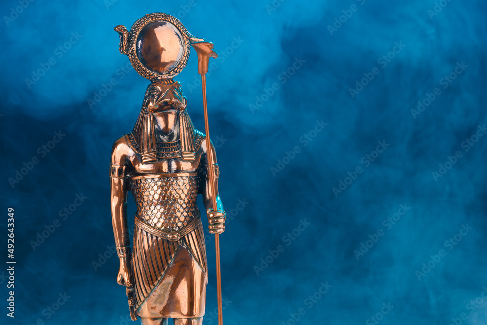 gold Egyptian figurine of the god RA with the head of a falcon in blue ...