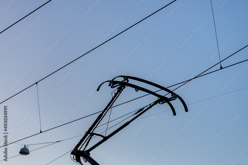 Pantograph of a tram connecting on electric line with blue sky as ...