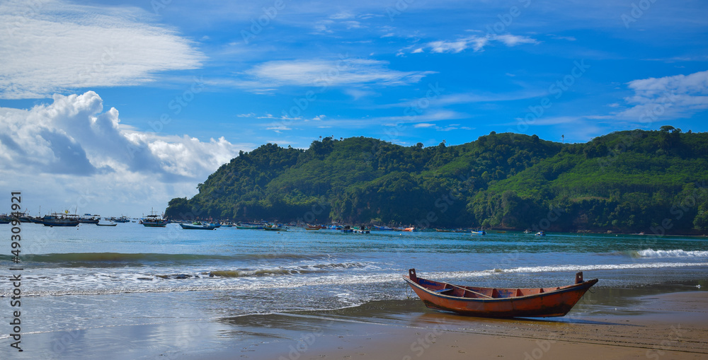 Traditional wooden fishing boats and beautiful hilly beach in East Java ...