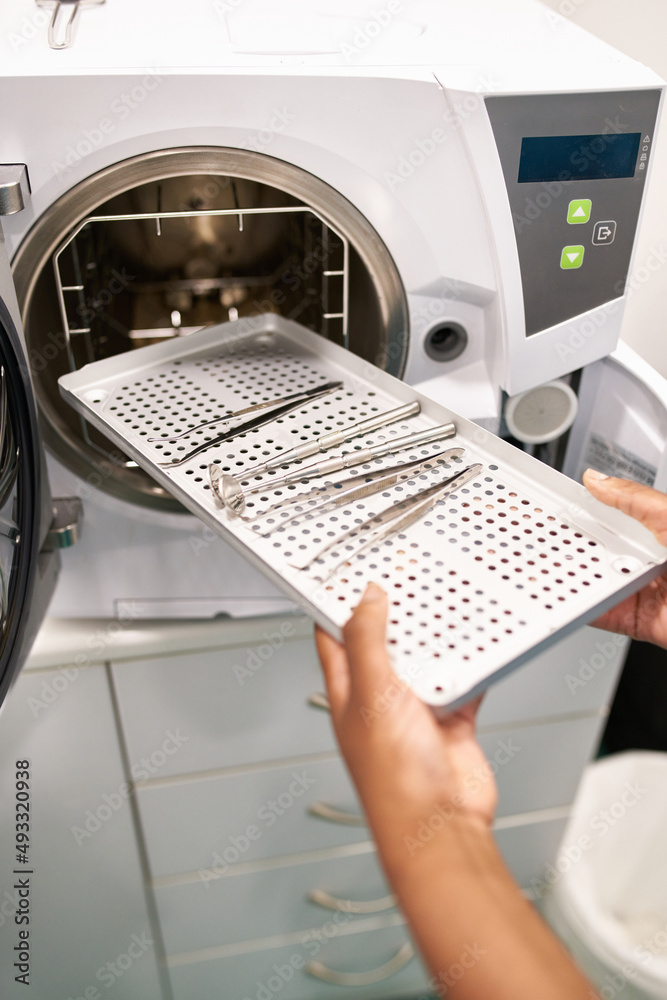 Crop dentist sterilizing tools in autoclave Stock Photo | Adobe Stock