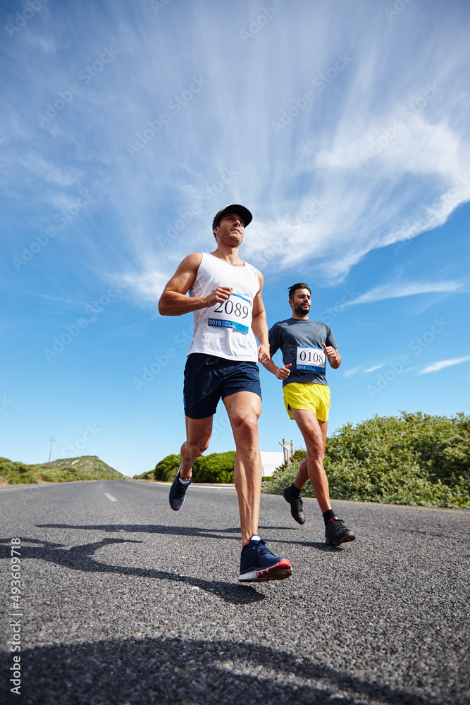 Hes catching up. Shot of a group of young men running a marathon. Stock ...