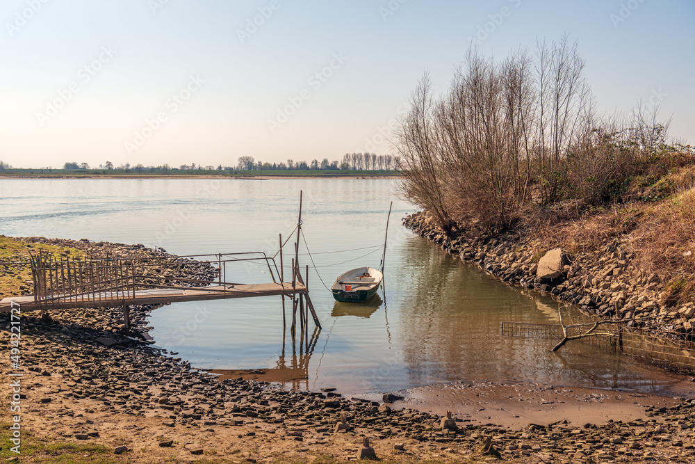 Simple wooden jetty with a rowing boat in a small cove of the wide ...