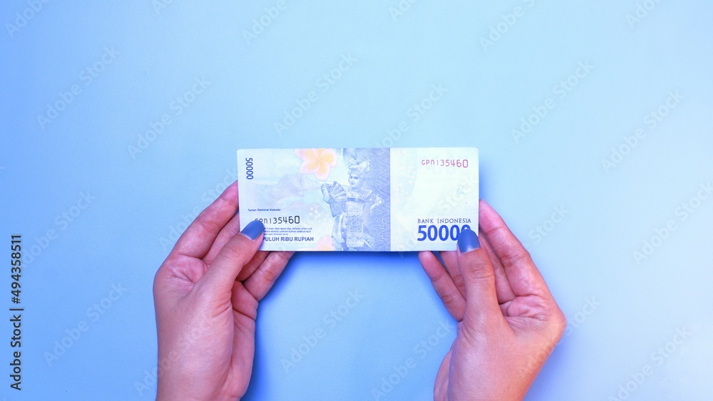 Indonesian Rupiah the official currency of Indonesia. woman's hand is ...