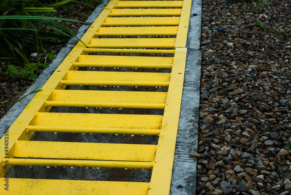 Drainage system for water removal. Yellow metal grate on a concrete ...