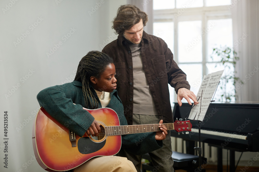 Teacher pointing at sheet music while his student learning to play the ...