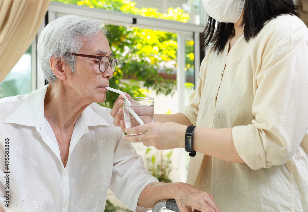 Asian caregiver take care of senior woman give drinking water from a ...