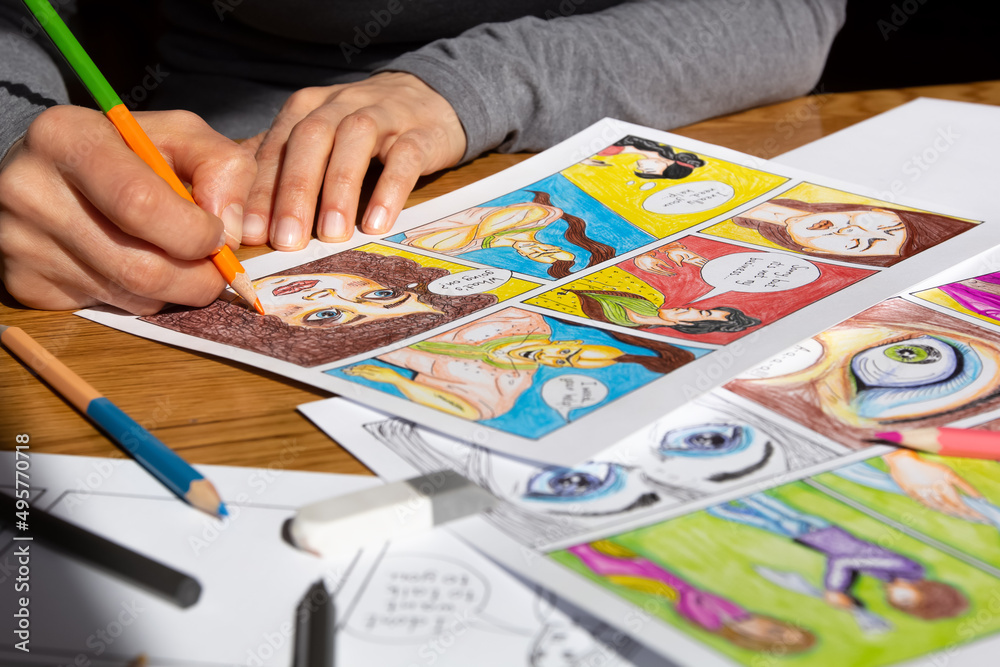 An artist draws comic book characters on paper with a pencil ...