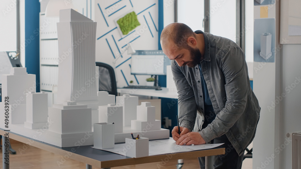 Man engineer analyzing building model to design blueprints plans on ...