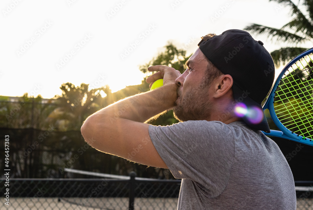 Adult man tennis player holds tennis ball and racquet in hands and ...