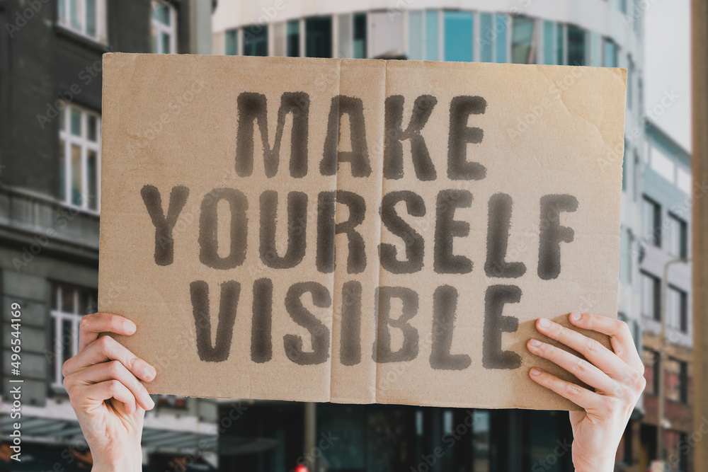 The phrase " Make yourself visible " on a banner in men's hands with blurred background. Share ...