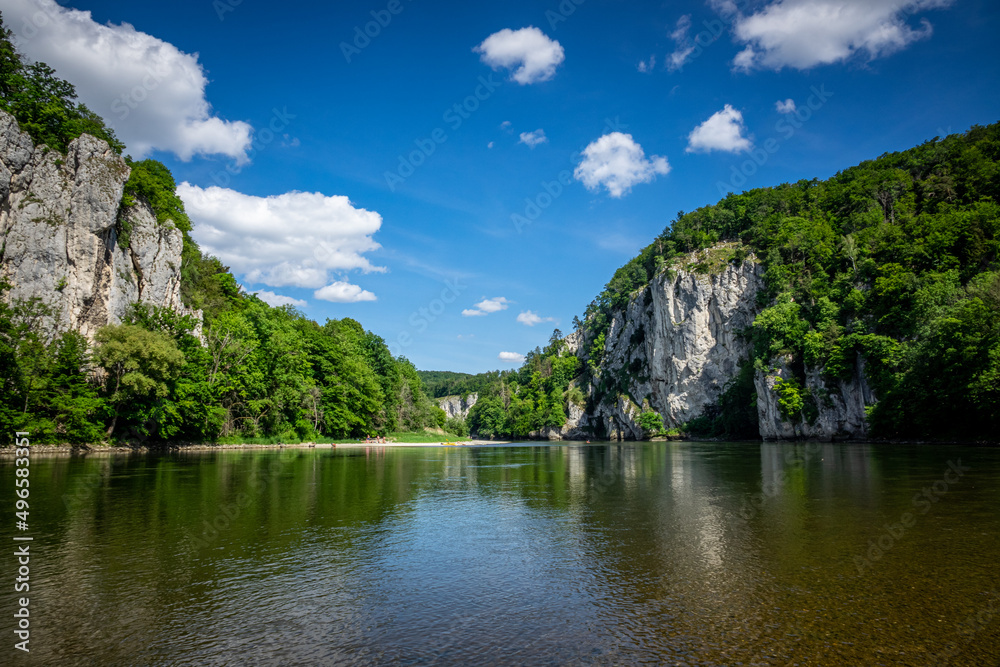 Rocks of the Danube Gorge with green forest, blue sky, water and beach ...