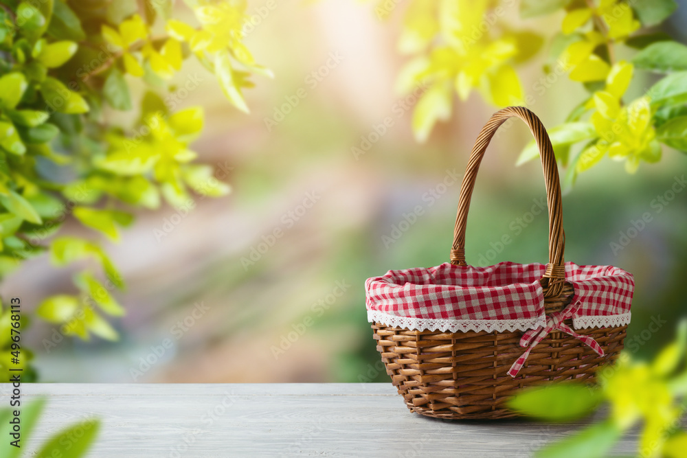 Empty picnic basket on wooden table over green leaves background ...