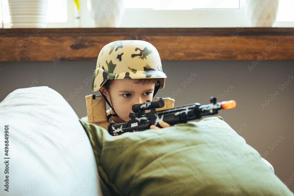 Little boy playing soldiers in living room. In his imagination the boy ...