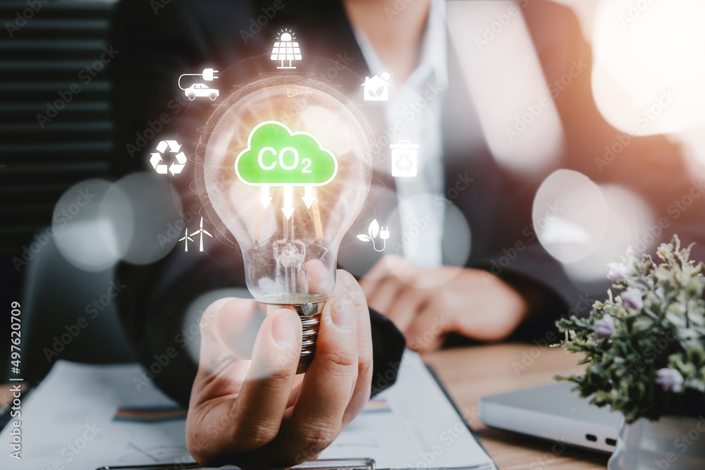 Reduce CO2 emission concept, Person hand holding light bulb with CO2 icon on virtual screen ...