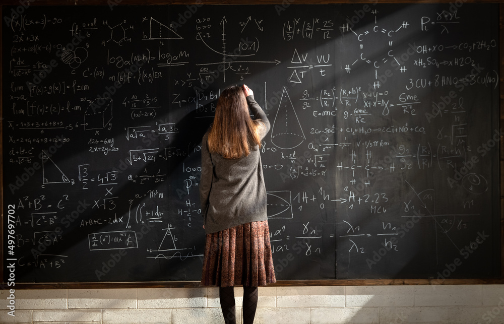 Cinematic shot of young female teacher is writing math formulas and ...