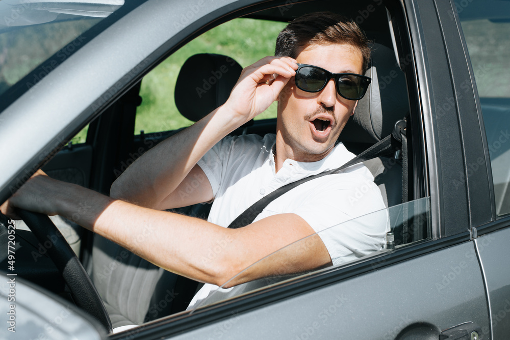 Caucasian young man driving car with surprised, shocked expression and ...