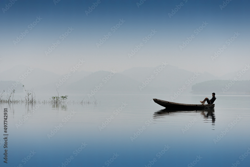 Zen . silhouette of a alone blue serenity fisherman in a lake of ...
