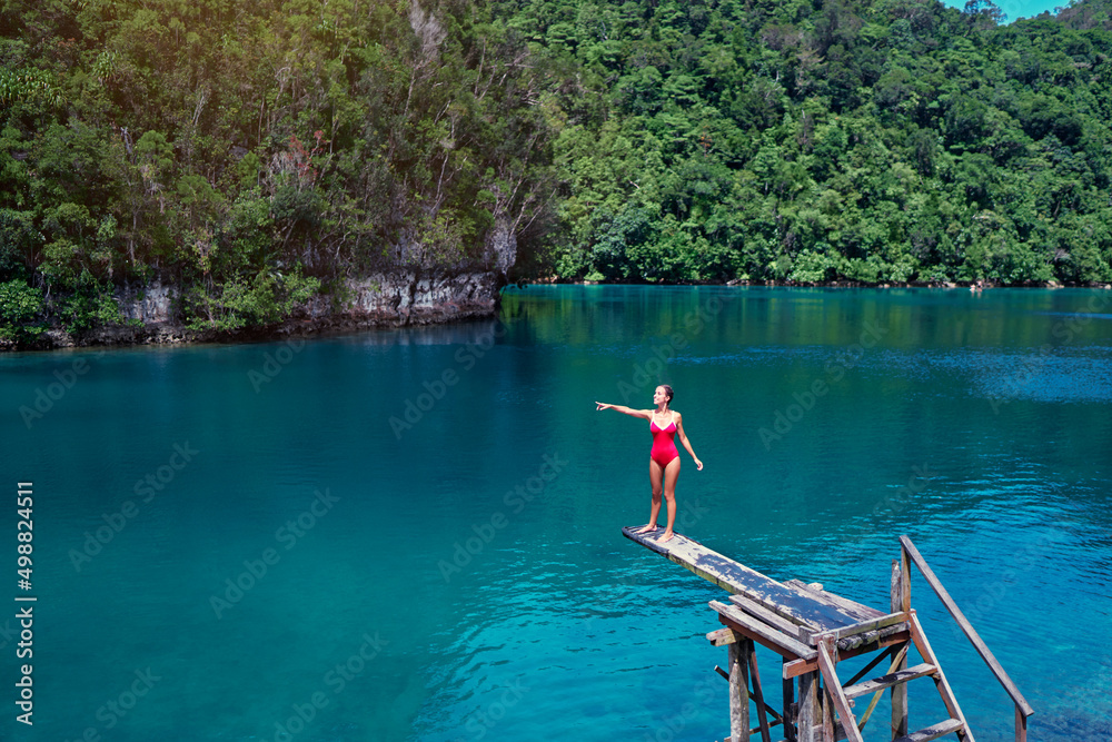 Vacation and activity. Young woman in swimsuit enjoying blue tropical ...
