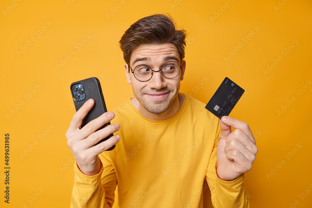 Safe mobile banking concept. Pleased brunet man holds smartphone and ...