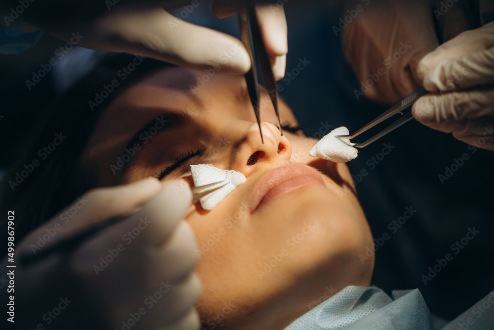 Surgeon and his assistant performing cosmetic surgery on nose in ...