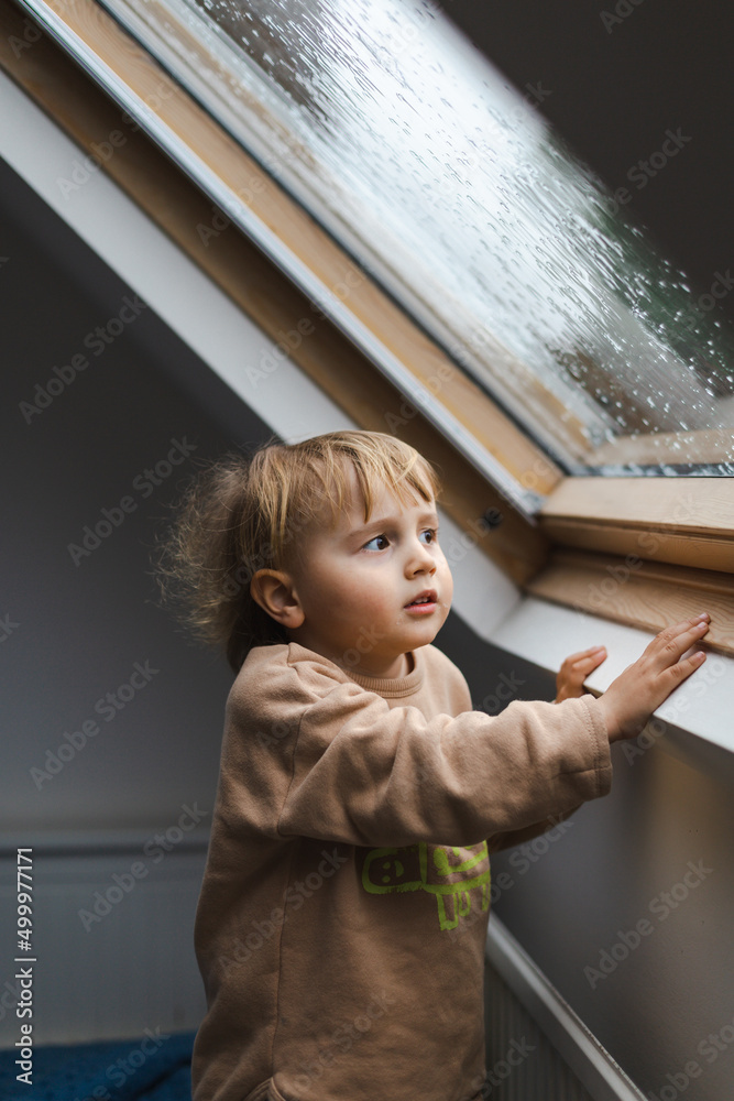 Little preschool boy staying home in bad weather and looking with ...