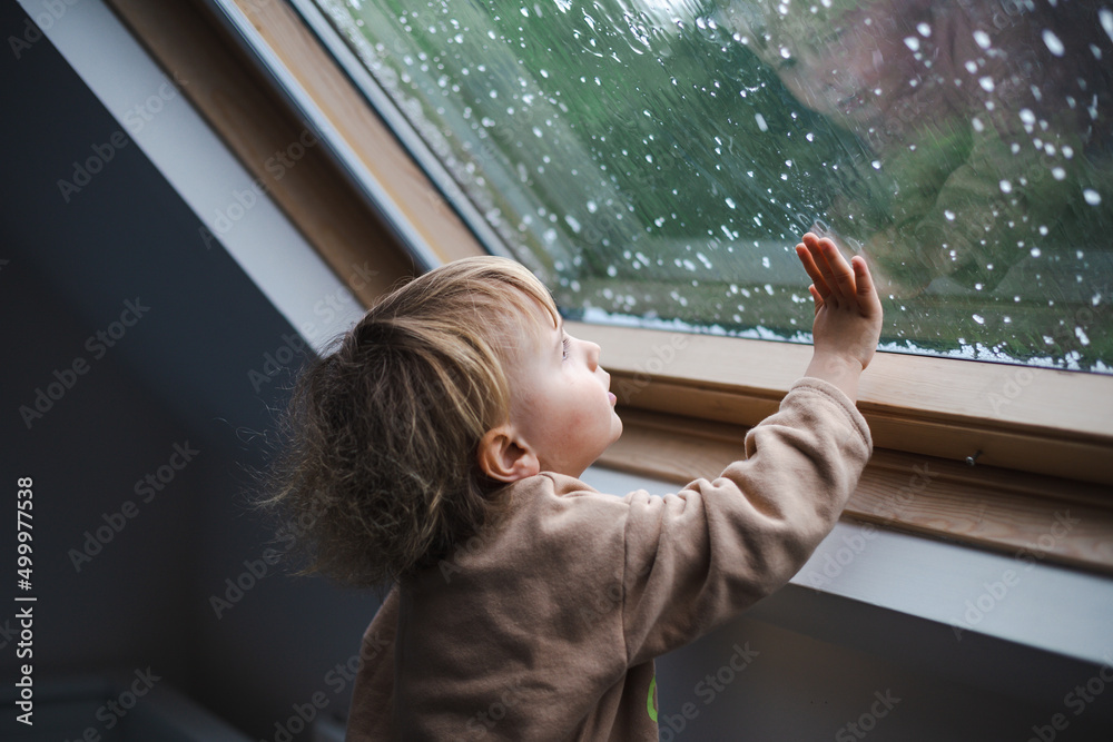Little preschool boy staying home in bad weather and looking with ...