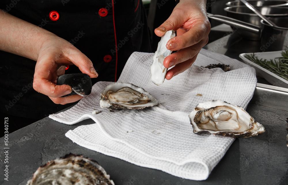 Opening the hollow and flat oysters. Chef opens oysters in the ...