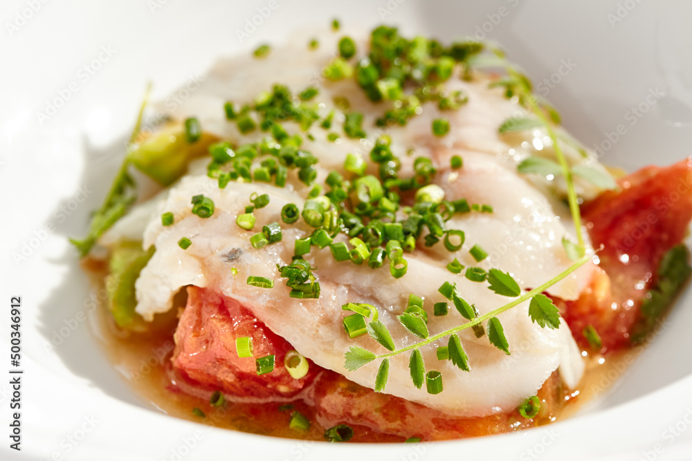 Healthy dinner - fish fillet with tomato and avocado on white plate ...