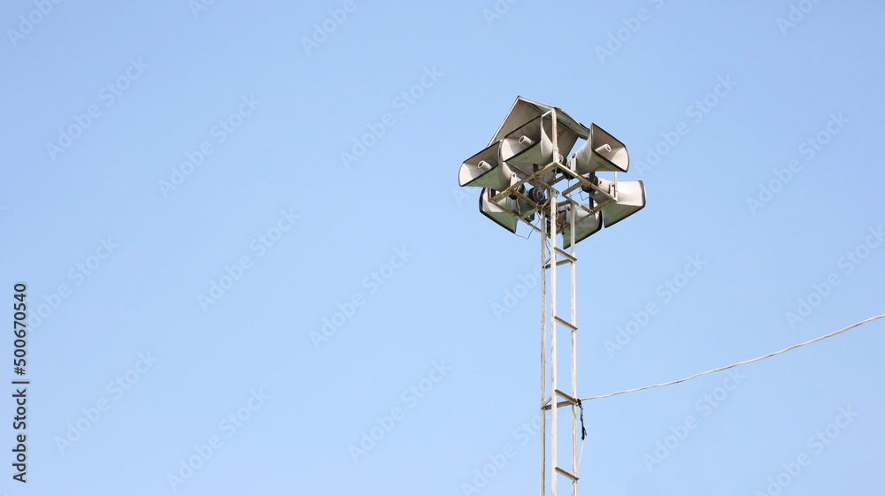 Horn speakers on the tower. Lots of white horn speakers on a steel ...