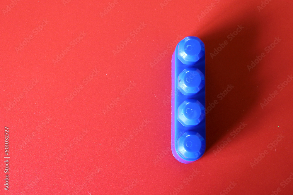 Buildable blue plastic block on a red background. Concept of loneliness ...