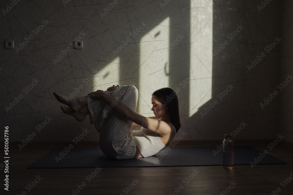 Full body of tranquil woman lying on mat in Wind relieving pose or ...