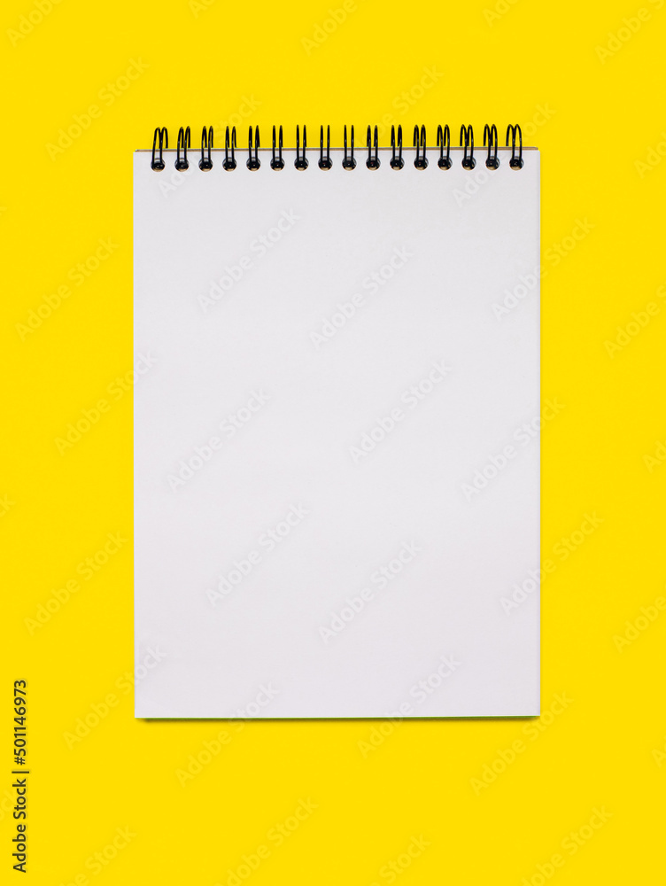 Notebook made of white paper with binding on a yellow background. Blank ...