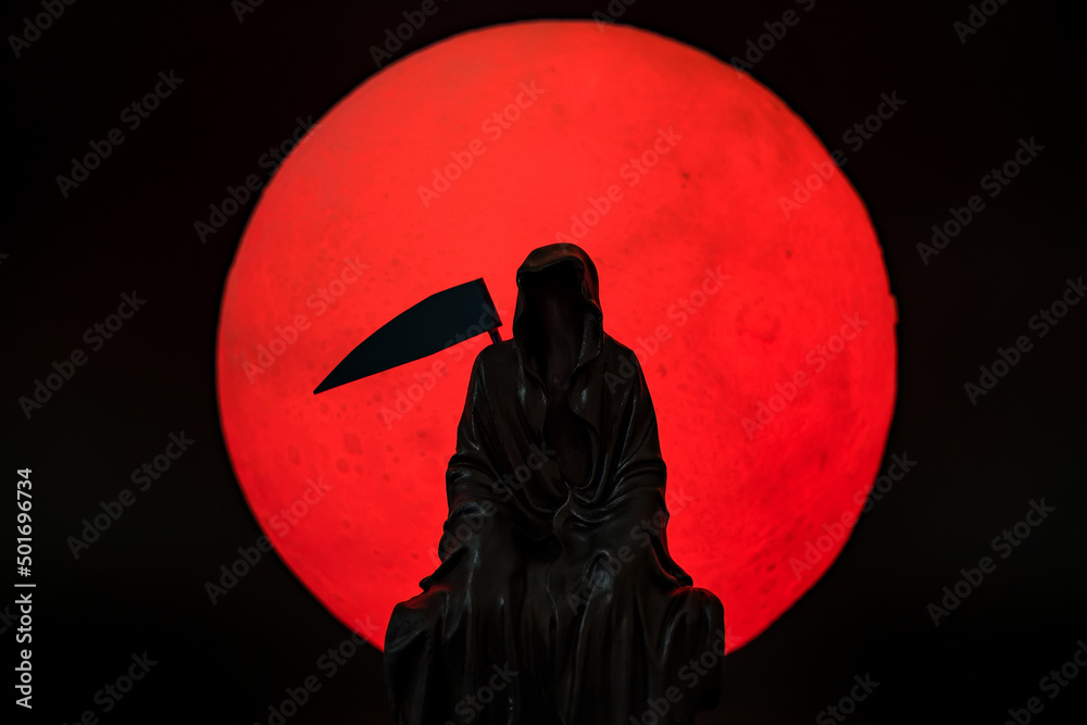 A statue of a grim reaper sitting on a full moon background. Stock ...