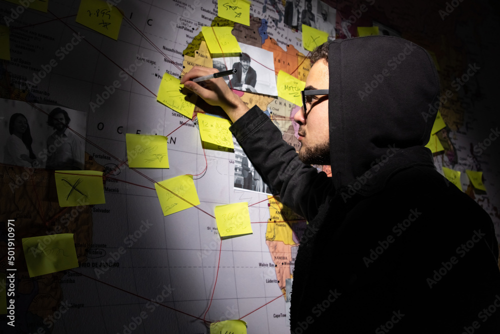 Side view of man planning hacker attack in dark room. Man writing on ...