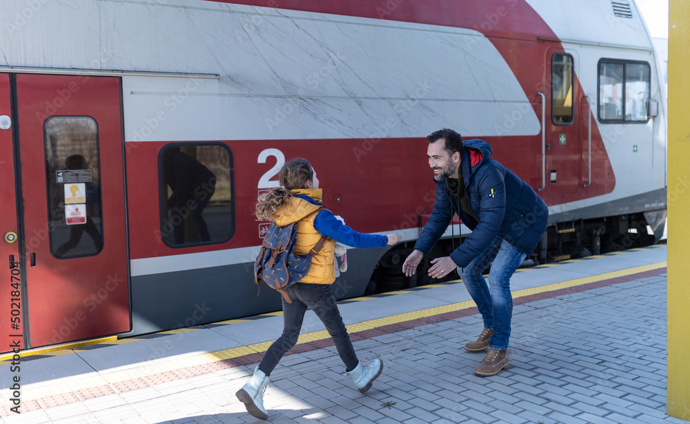 Happy Ukrainian refugee girl running to her father waiting at railway ...