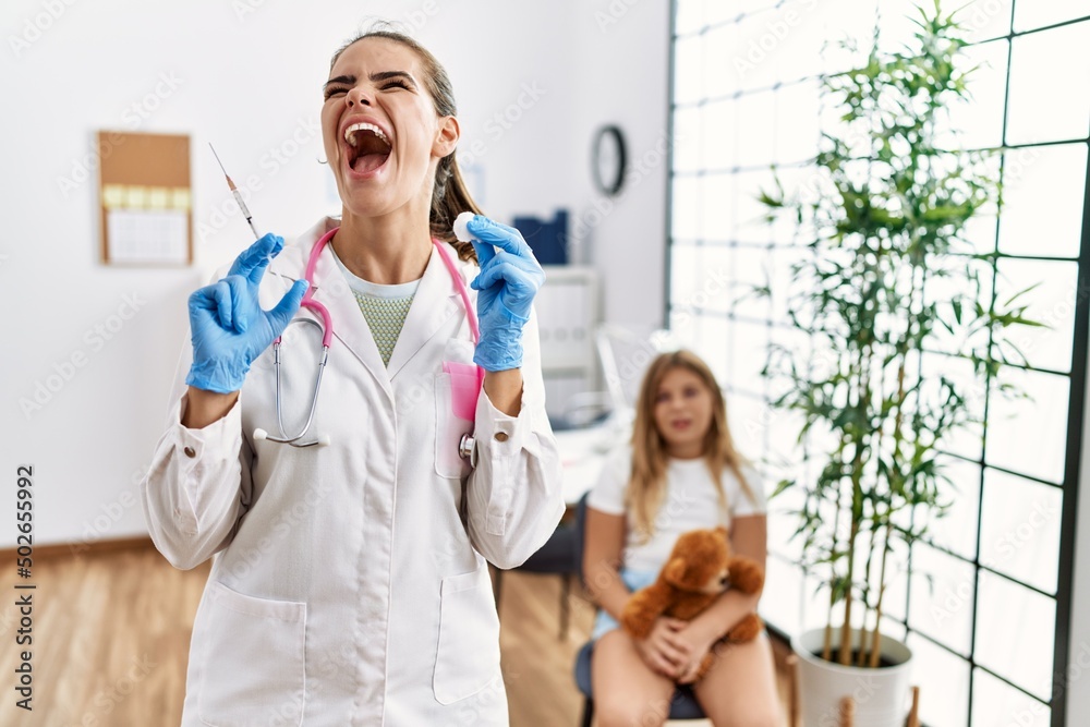 Young doctor woman putting vaccine to little girl angry and mad ...