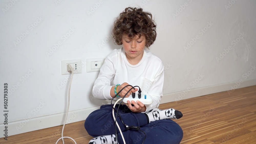 7-year-old child at home uses and plays with the electrical socket with ...
