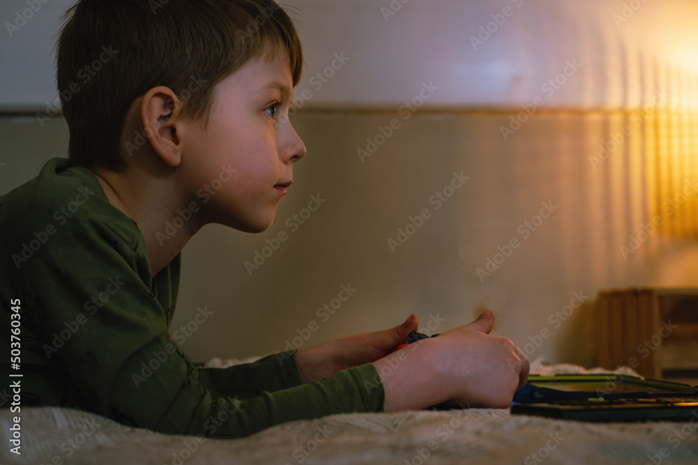 Kids playing video games at home on the bed at night. Boys using game ...