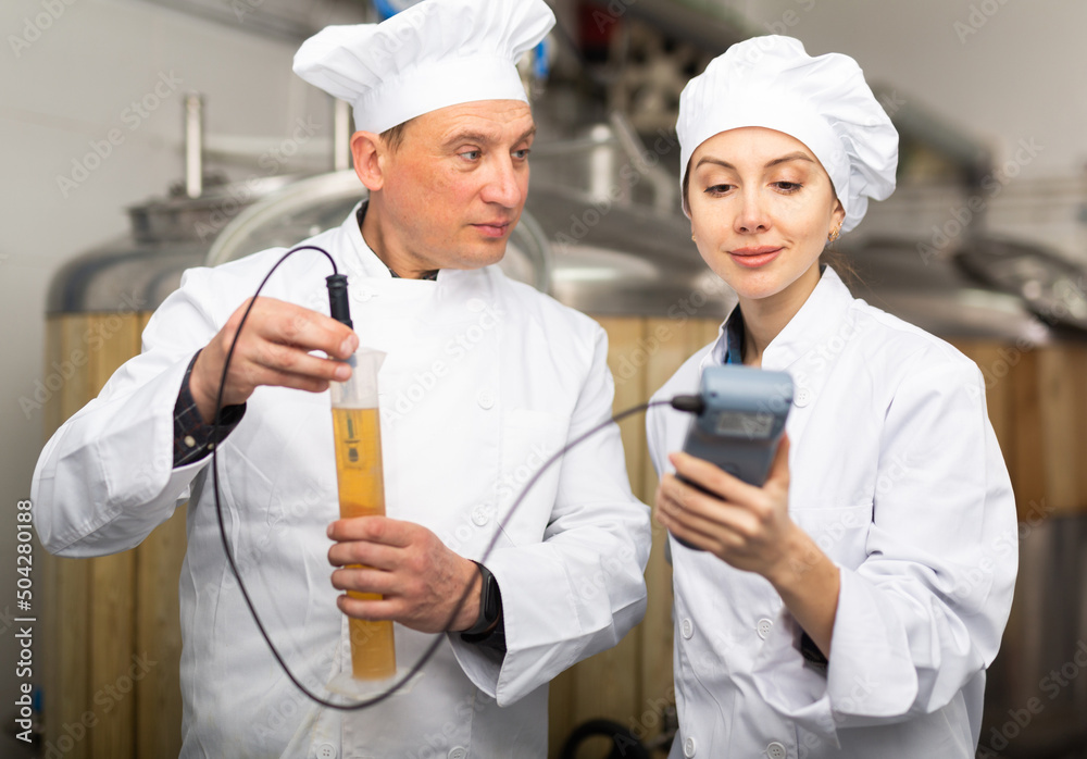 Interested focused male and female brewers wearing white uniform ...